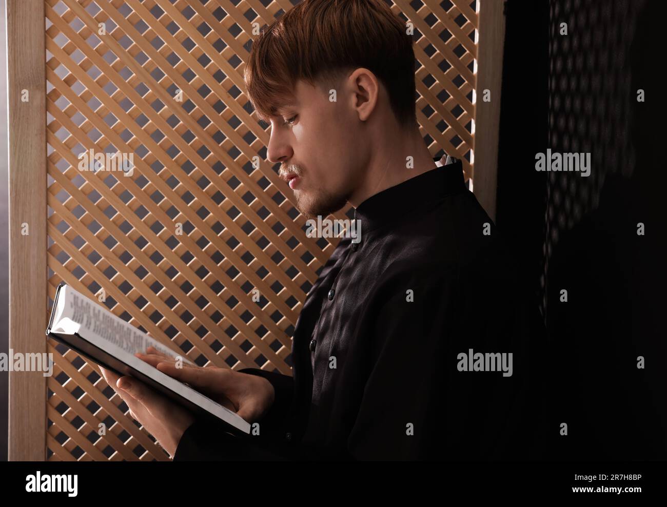 Catholic priest with Bible near wooden window in confessional Stock ...