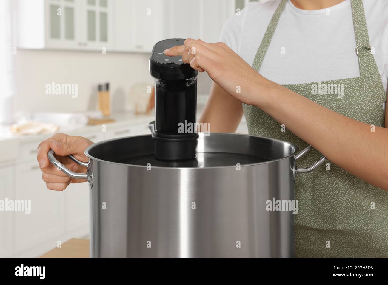 Woman using thermal immersion circulator in kitchen, closeup. Sous vide ...