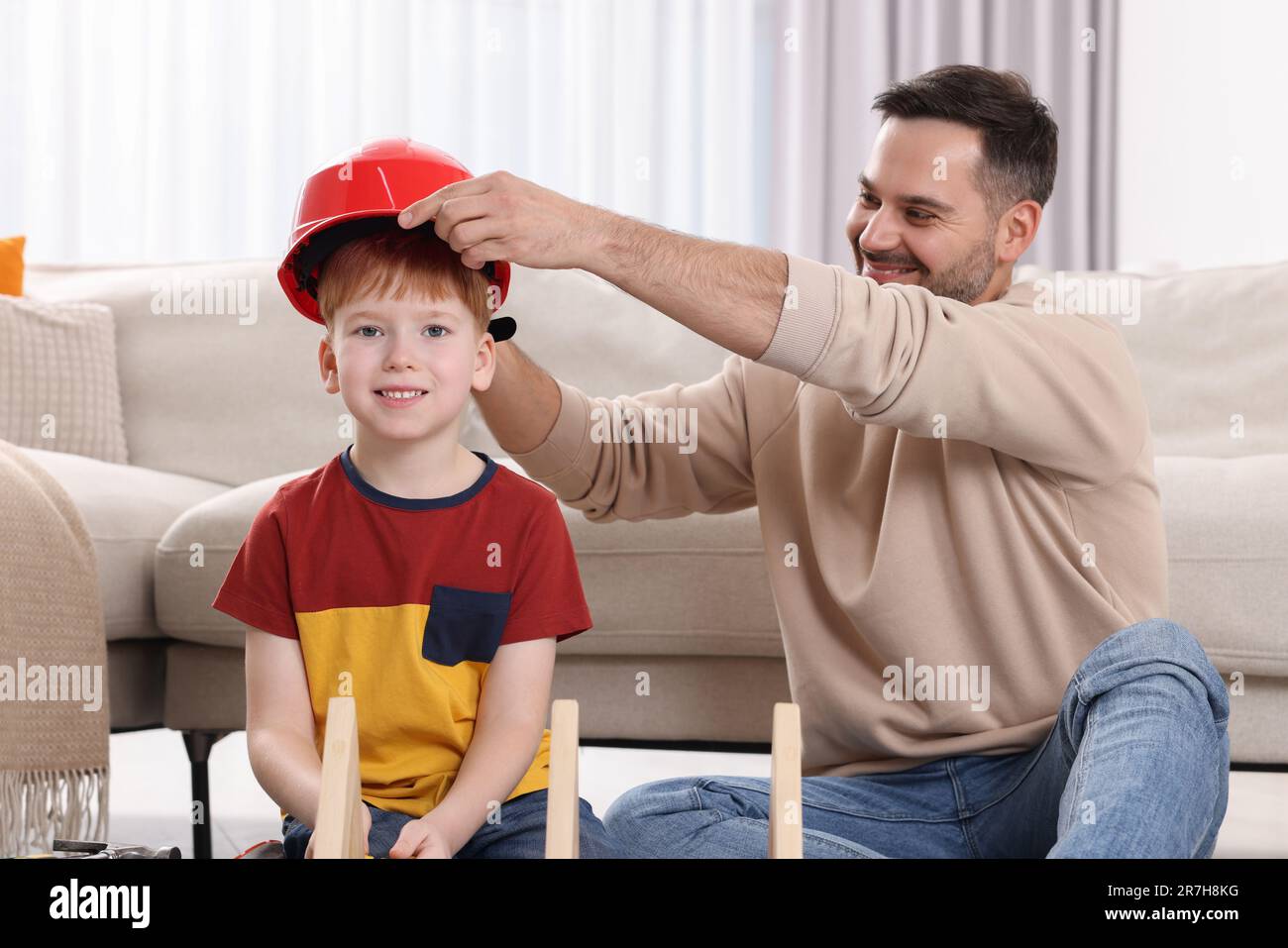 Father putting hard hat on his son at home. Repair work Stock Photo - Alamy
