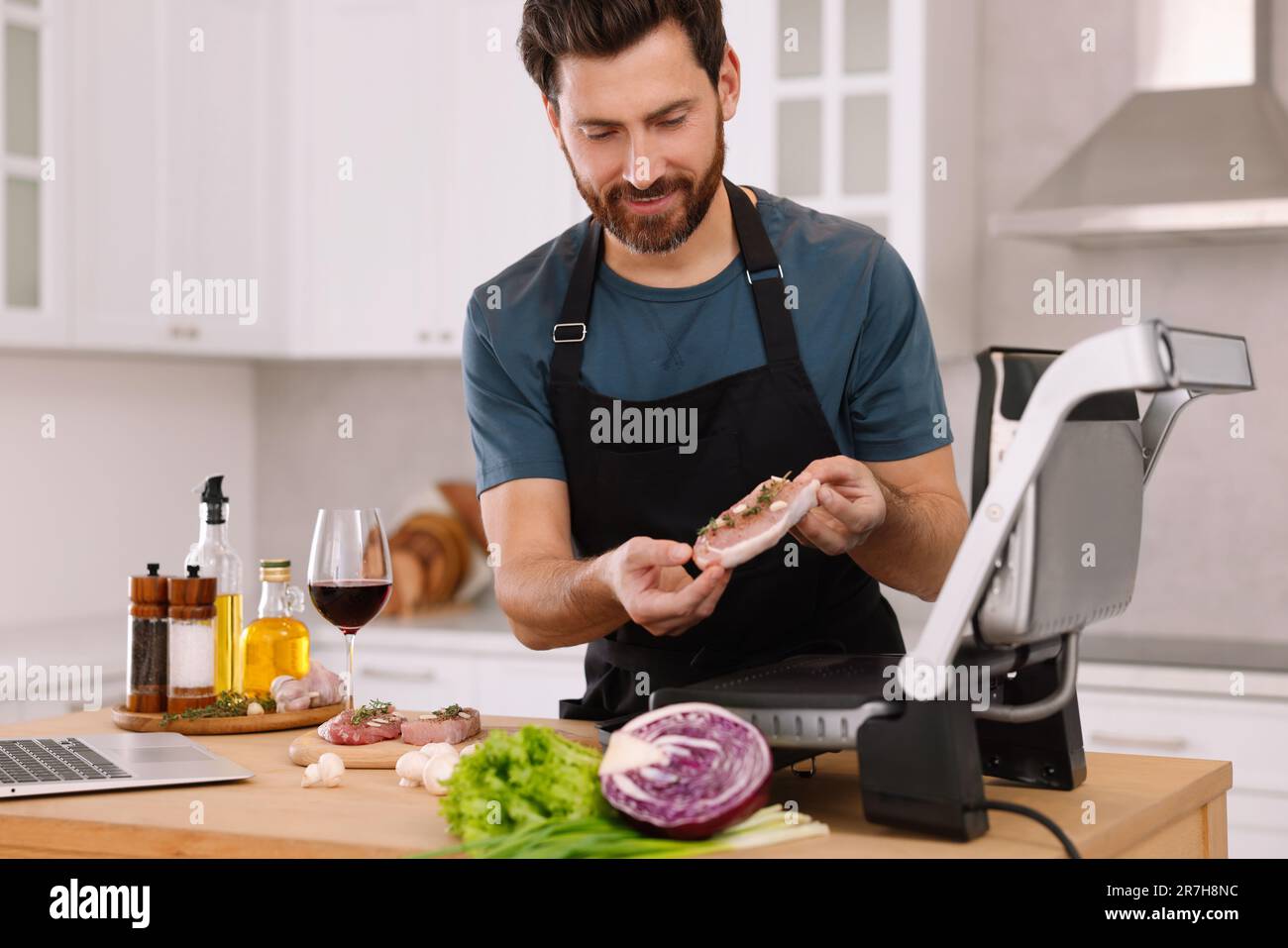Man making dinner while watching online cooking course via laptop in ...