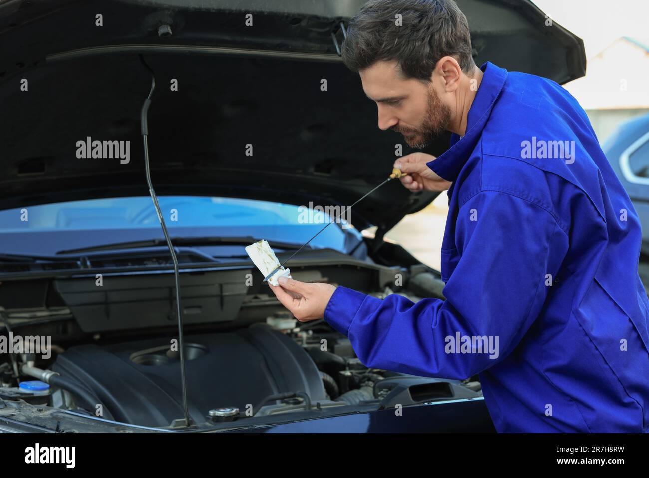 Worker checking motor oil level with dipstick outdoors Stock Photo - Alamy