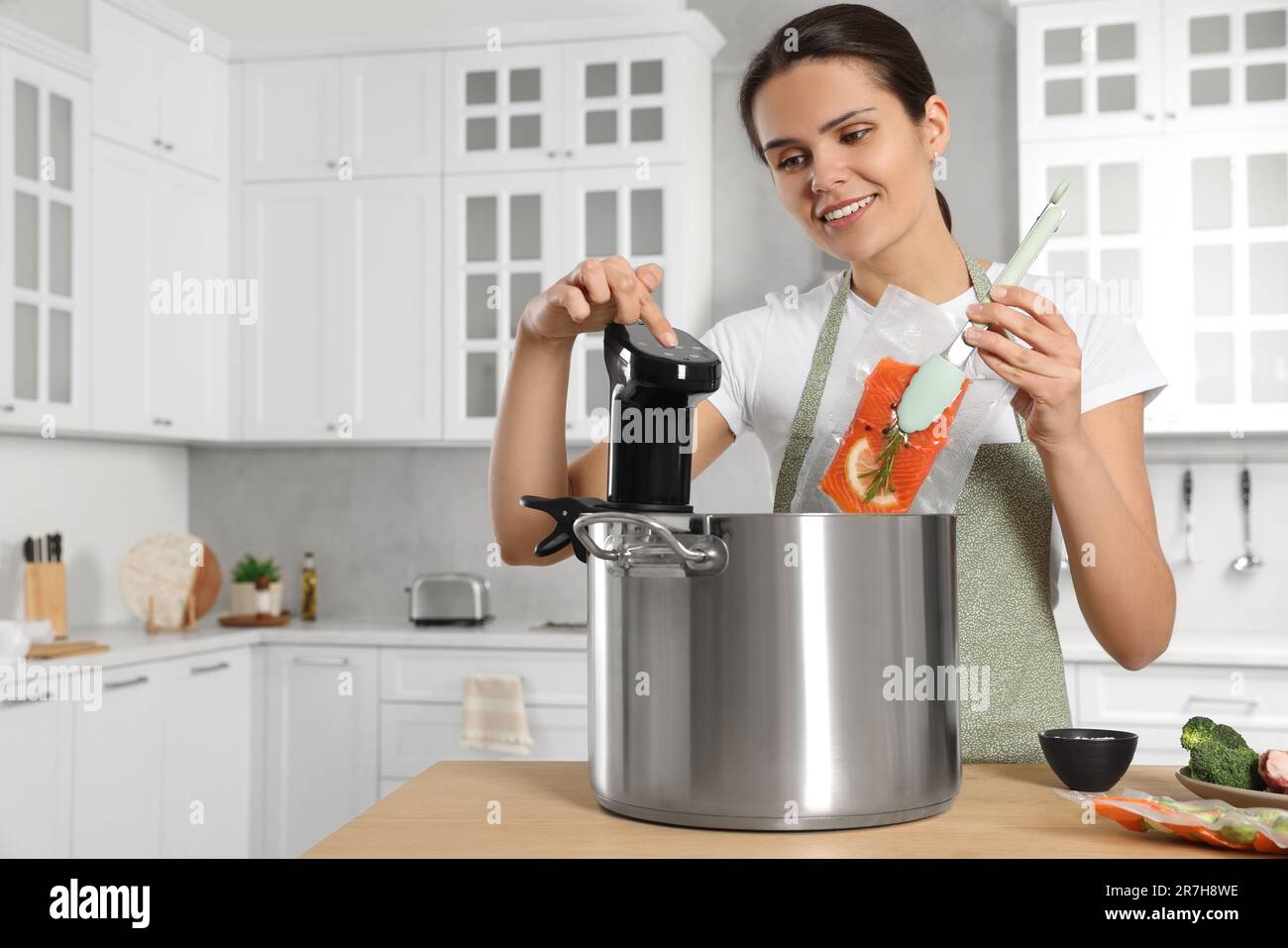 Woman putting vacuum packed salmon into pot and using thermal immersion ...