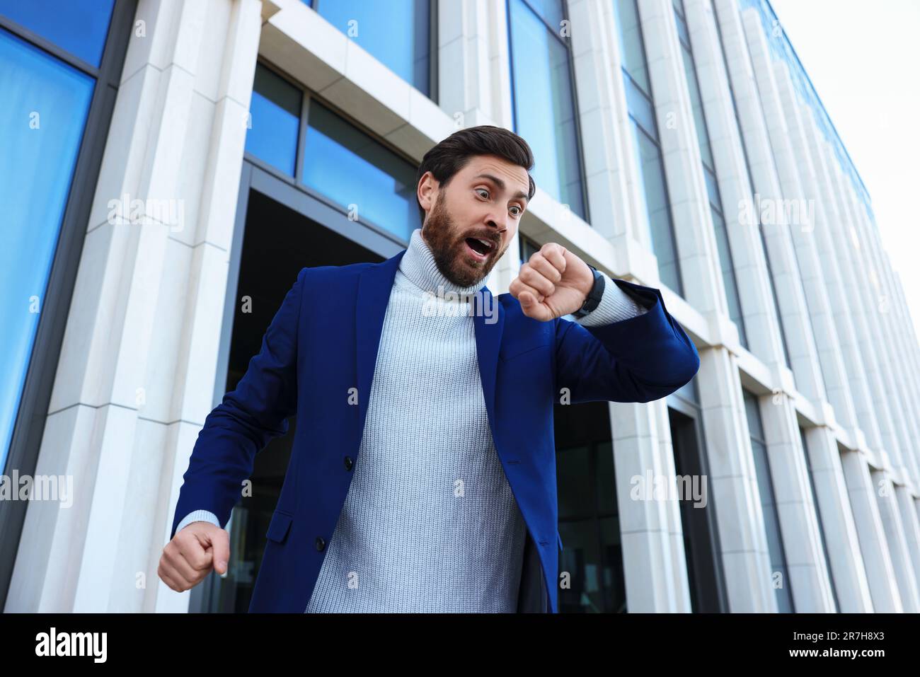 Emotional businessman looking at watch near building, low angle view ...