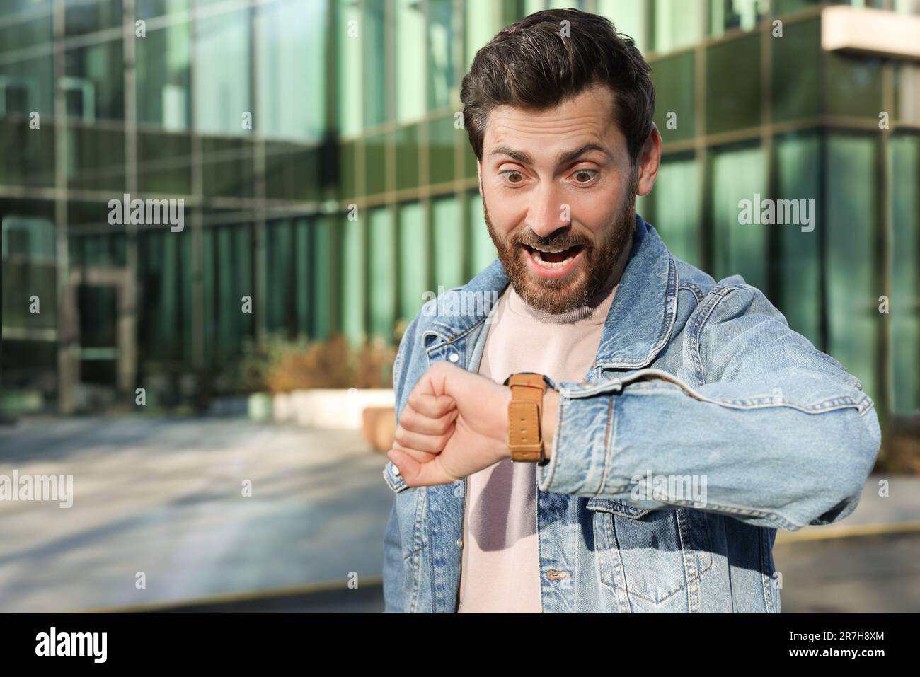 Emotional man checking time on watch near building. Being late concept ...