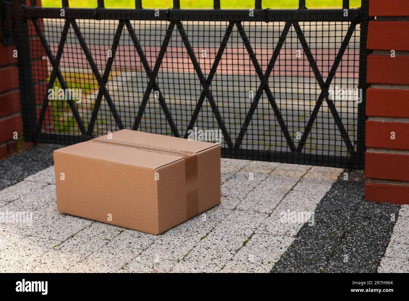 Cardboard boxes near front gates outdoors. Parcel delivery service ...