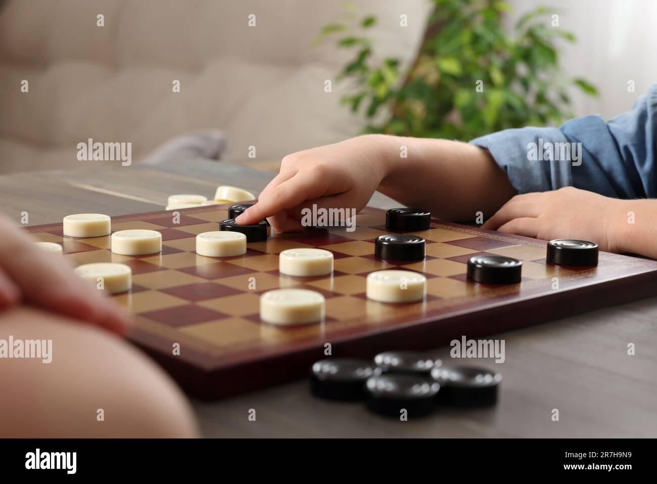 Children playing checkers at table in room, closeup Stock Photo - Alamy