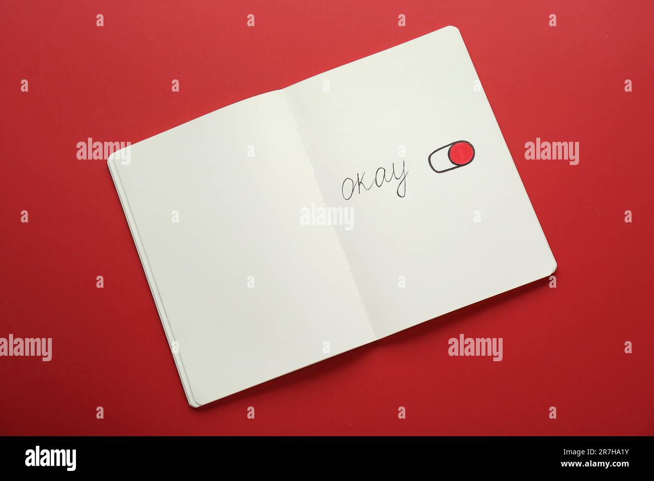 Notebook with word Okay and drawing of switch on button against red ...