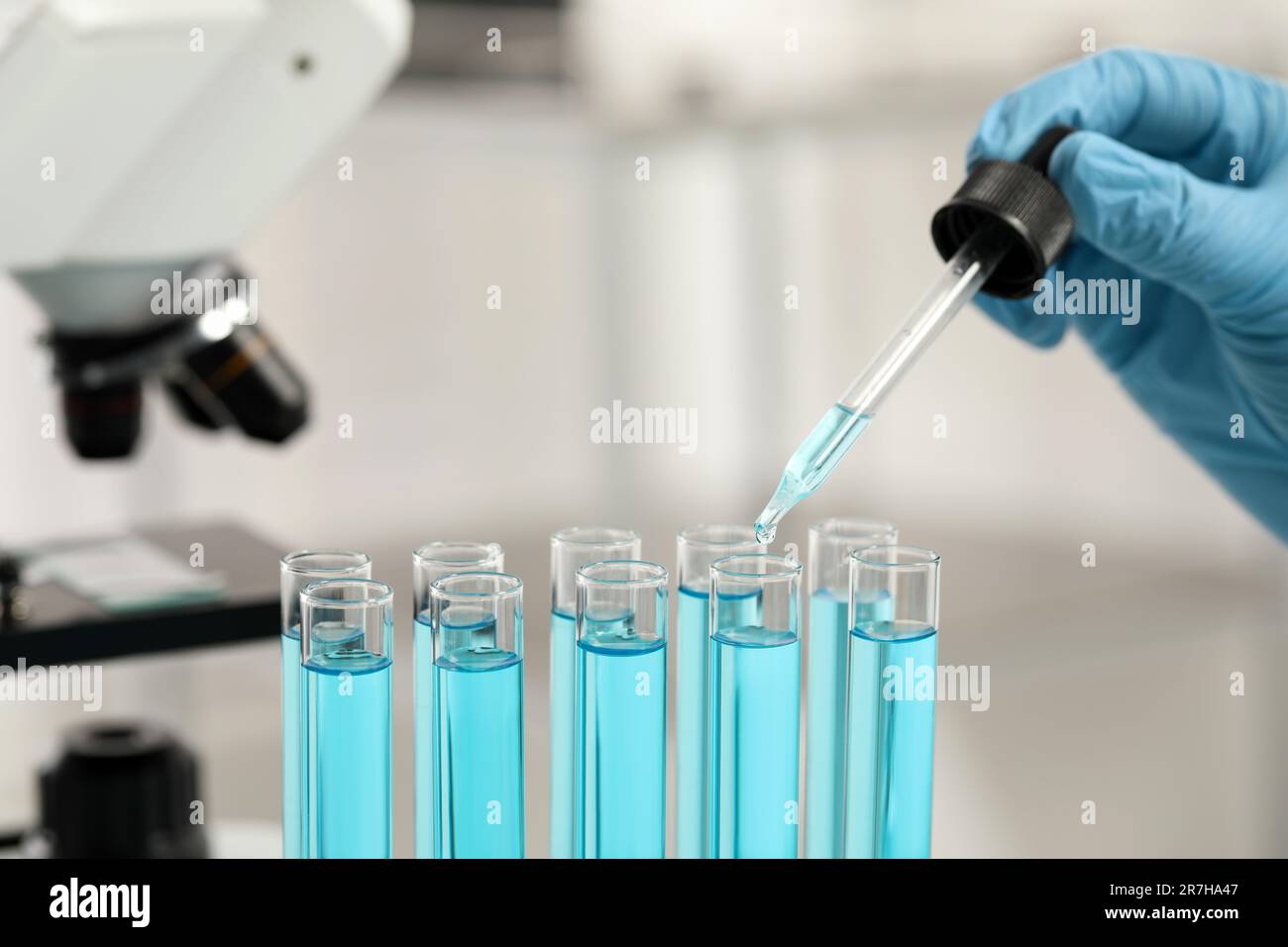 Scientist dripping liquid from pipette into test tube in laboratory ...