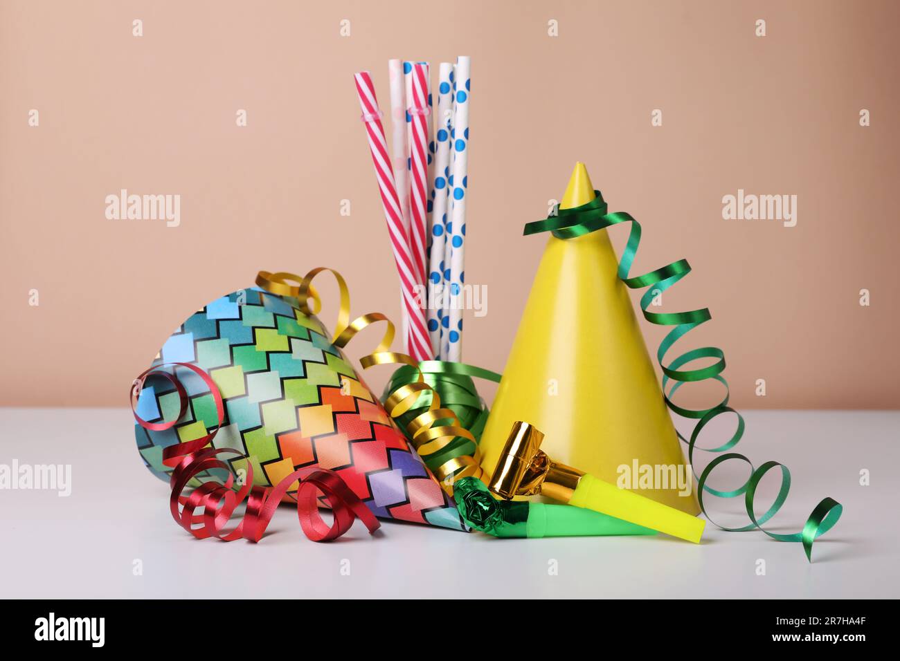 Colorful party hats, streamers and straws on white table. Birthday ...