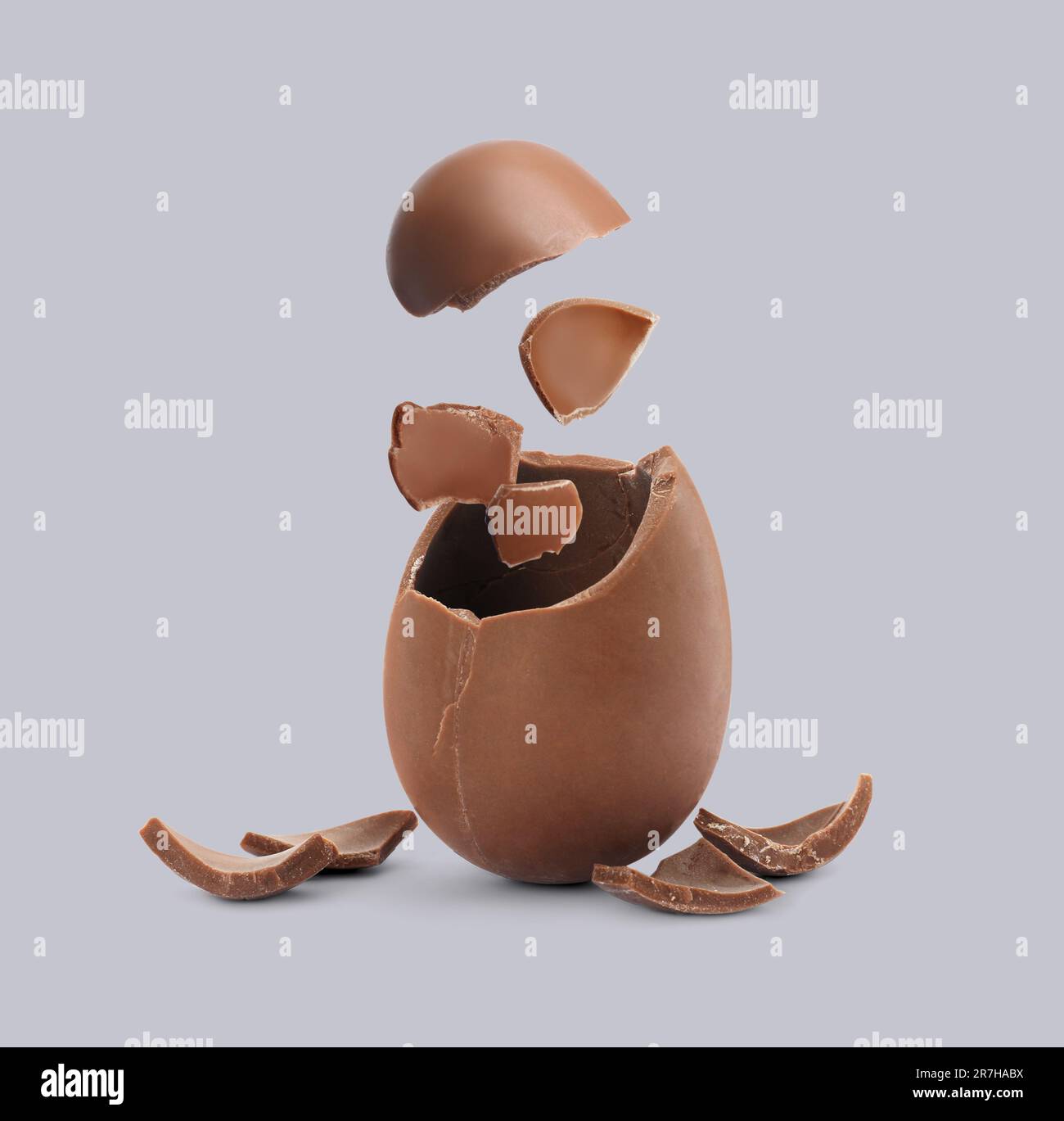 Exploded milk chocolate egg on grey background Stock Photo - Alamy