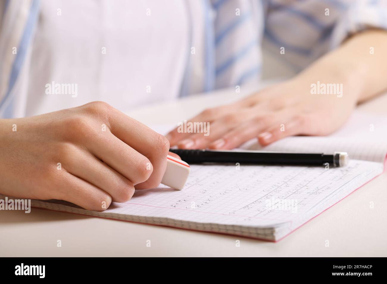 Girl erasing mistake in her notebook at white desk, closeup Stock Photo ...