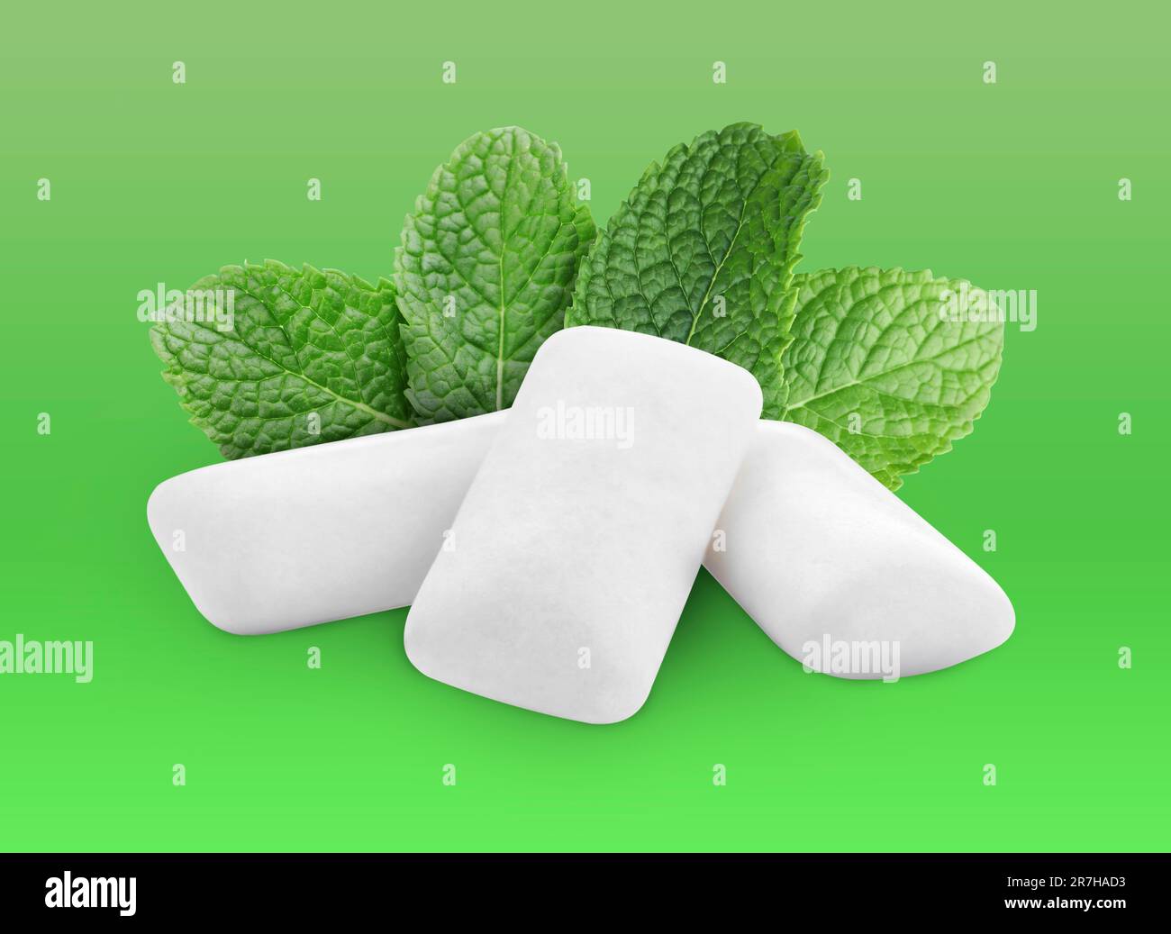 Menthol chewing gum pillows and mint leaves on green gradient ...
