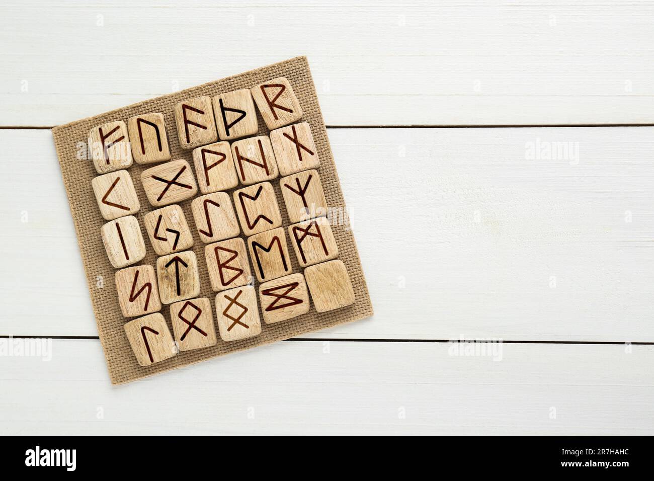 Runes with different symbols on white wooden table, top view. Space for ...
