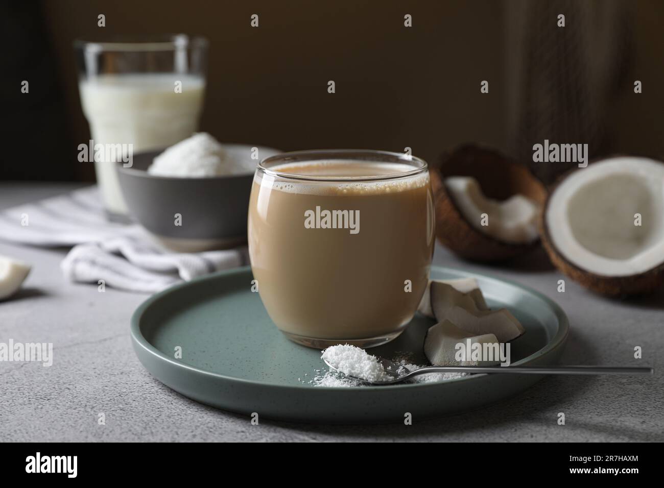 Glass of coffee with coconut milk, pieces and flakes on light grey ...