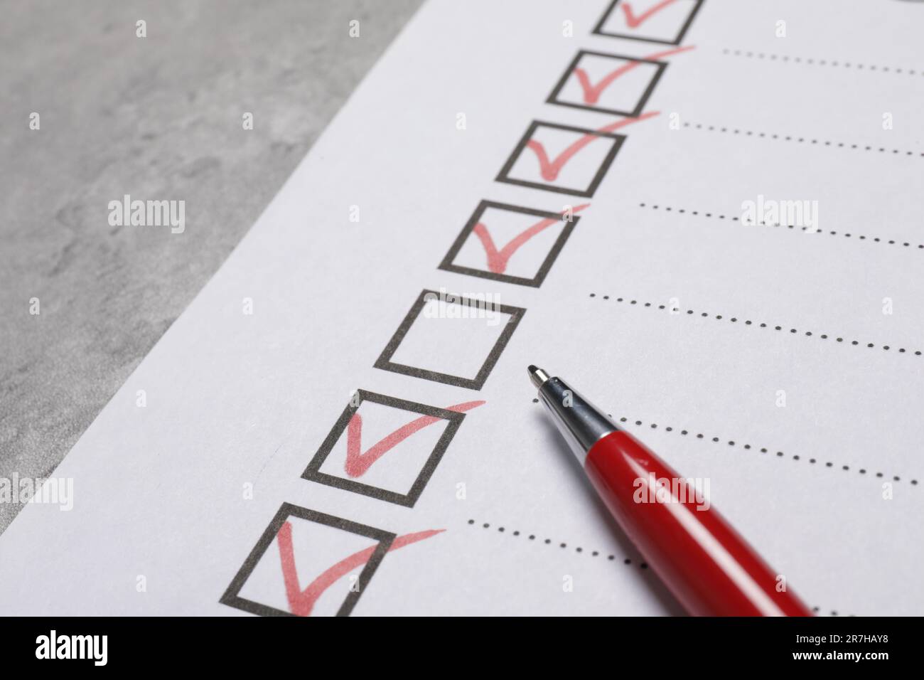 Paper sheet with checkboxes and pen on light grey table, closeup ...
