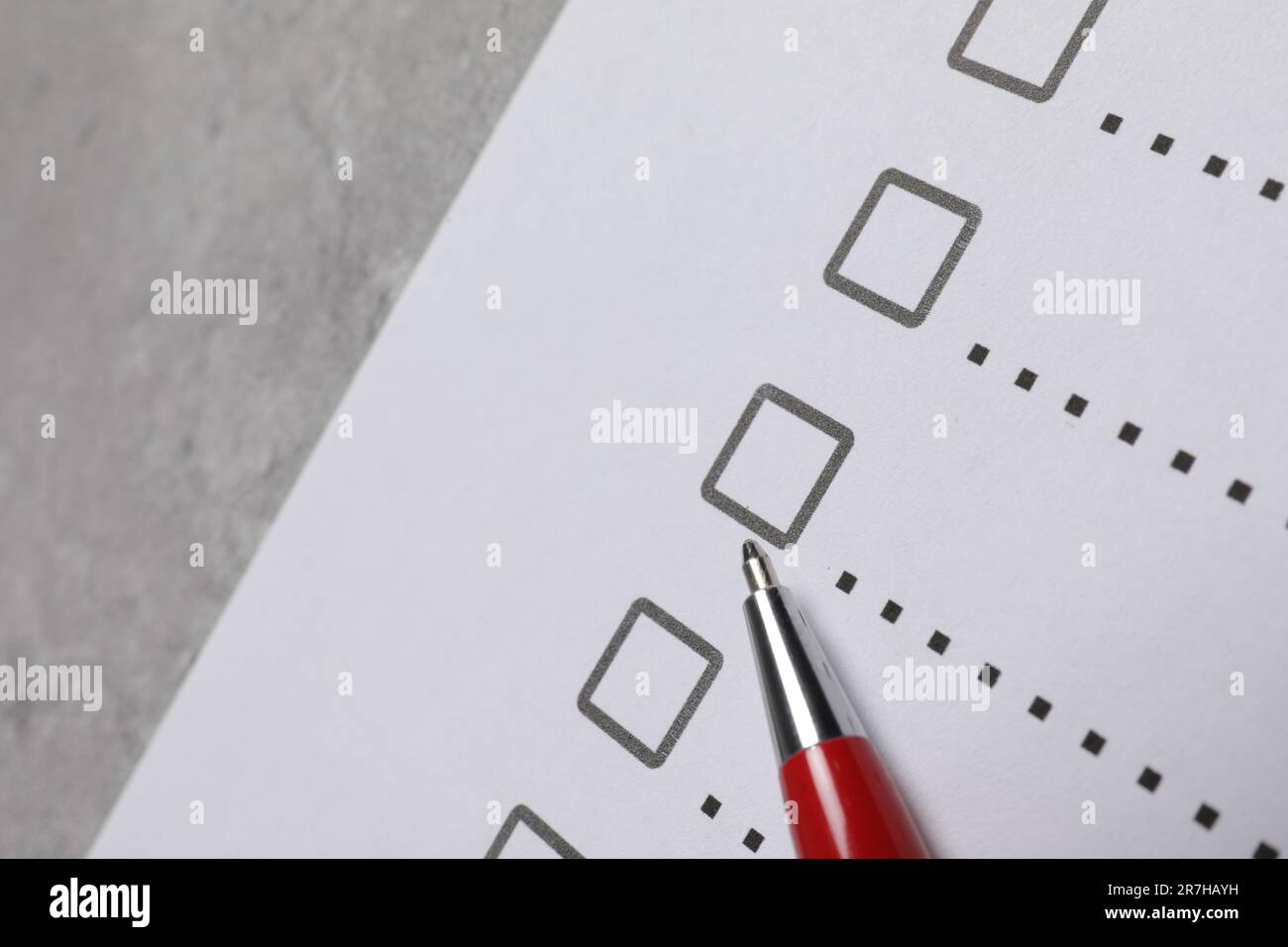Paper sheet with checkboxes and pen on light grey table, closeup ...