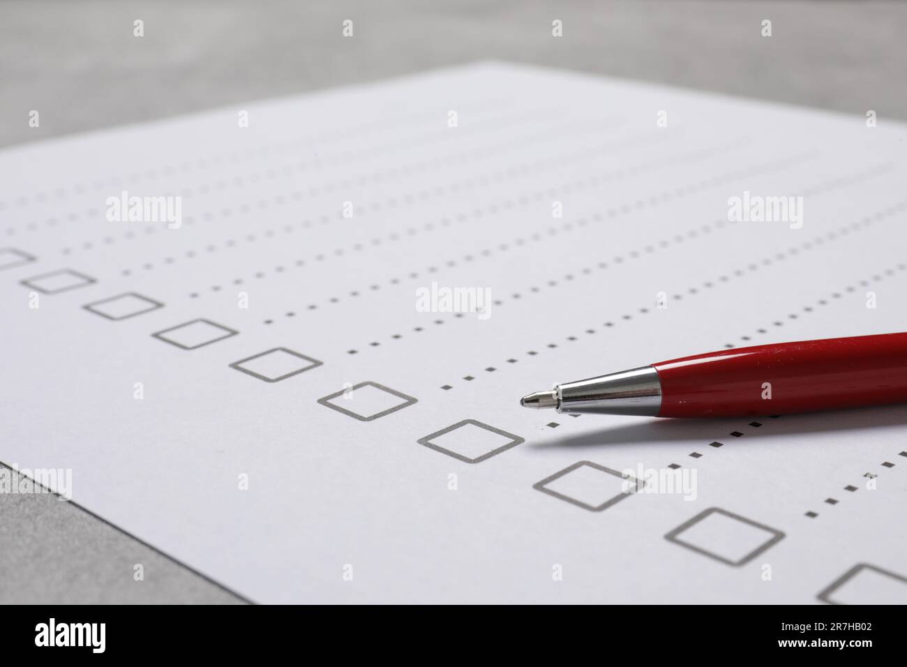 Paper sheet with checkboxes and pen on light grey table, closeup ...