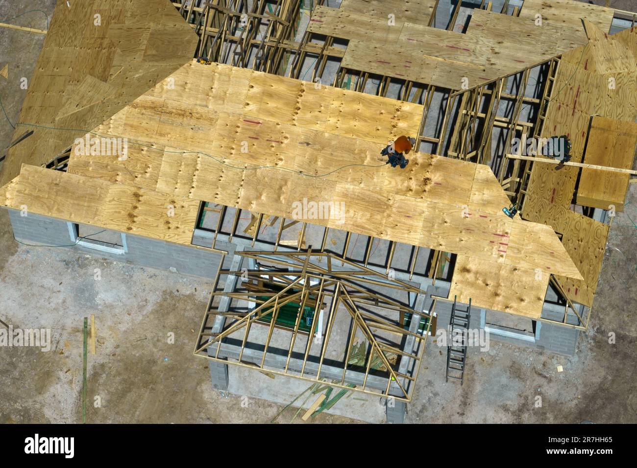 Aerial view of builders working on unfinished residential house with ...