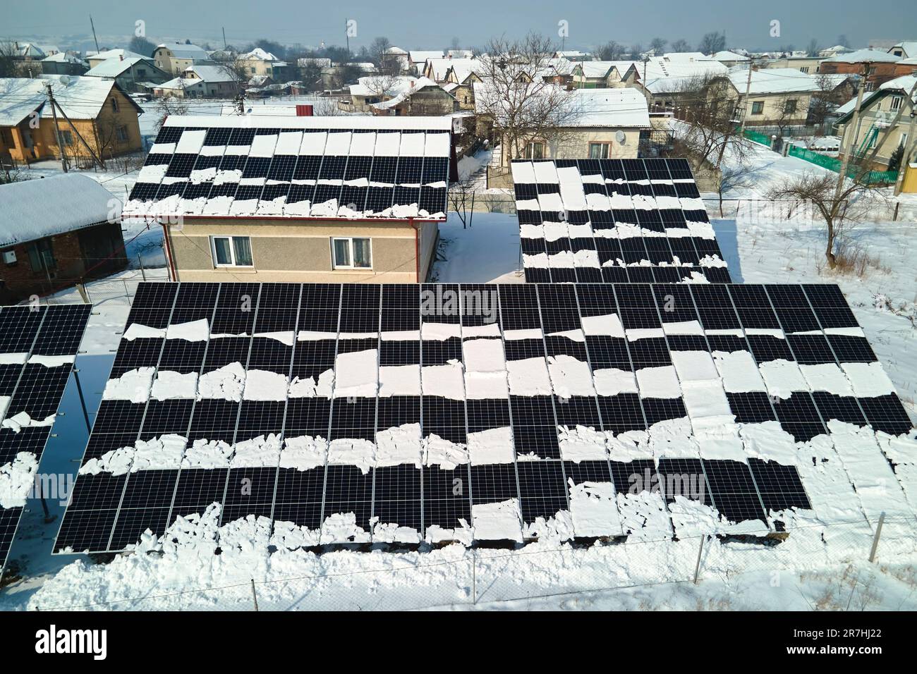 Aerial view of house roof with solar panels covered with snow melting ...