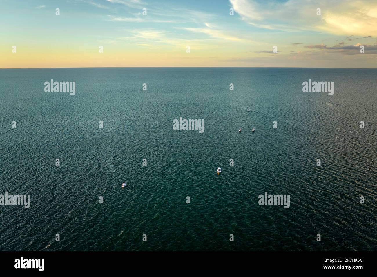 Aerial view of small yachts at sunset floating on sea waves with ripple ...