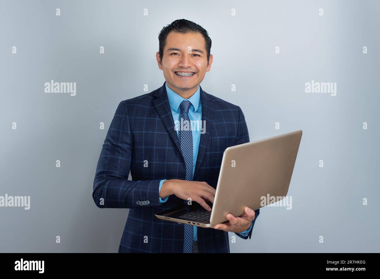 Young man with brown skin smiles dressed as a businessman with a laptop ...
