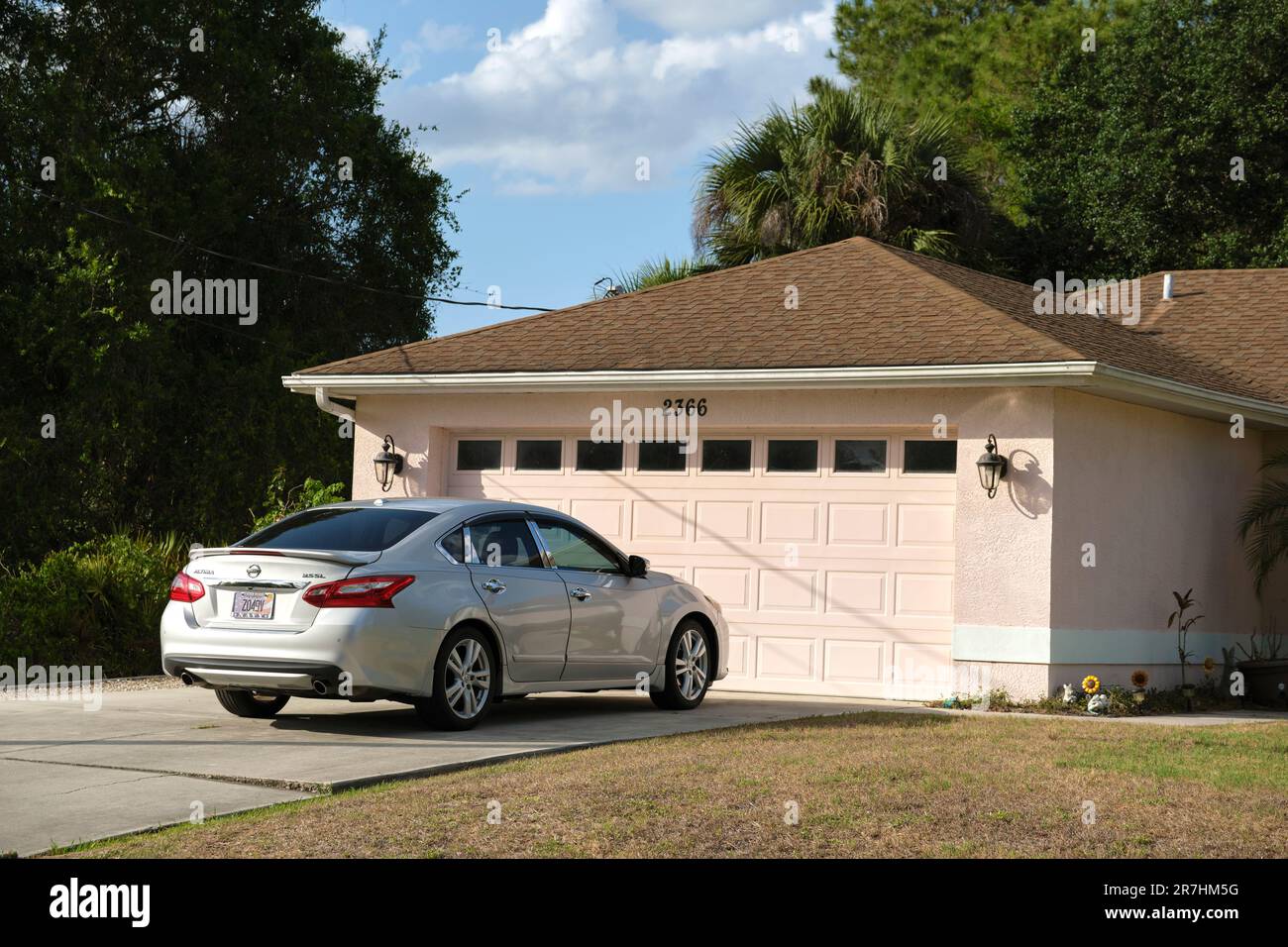 Car parked in front of wide garage double door on concrete driveway of ...