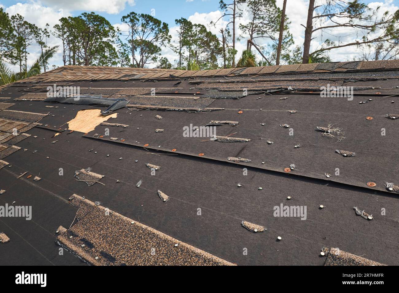 Damaged house roof with missing shingles after hurricane Ian in Florida ...