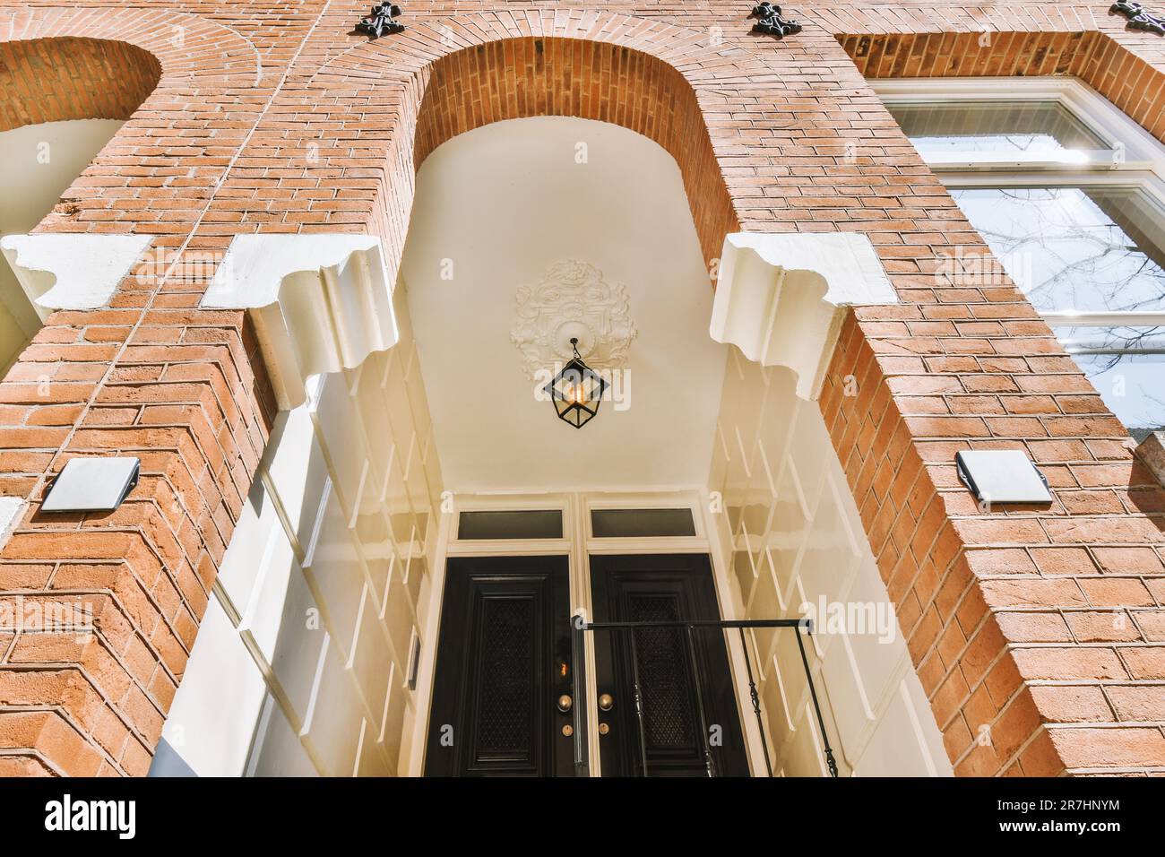 a clock hanging on the side of a brick building with white trim around ...