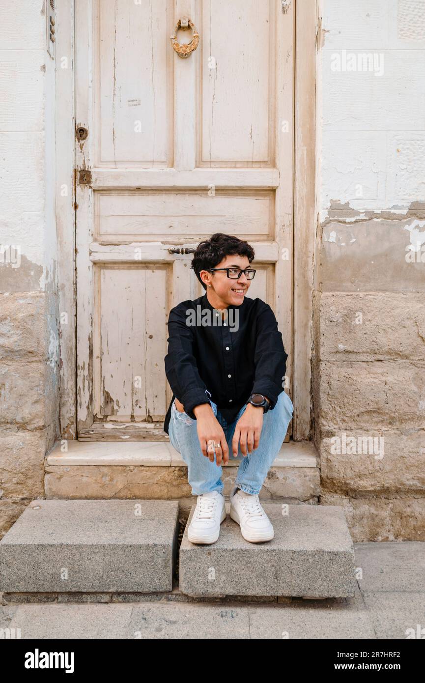 Young transgender man posing sitting on the front steps of a house ...