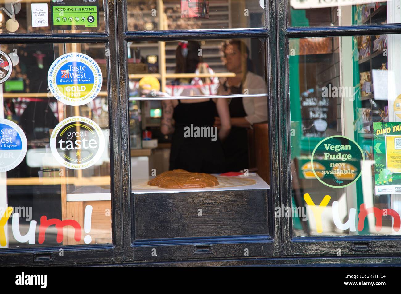 A young female adult stands in front of a restaurant window display ...