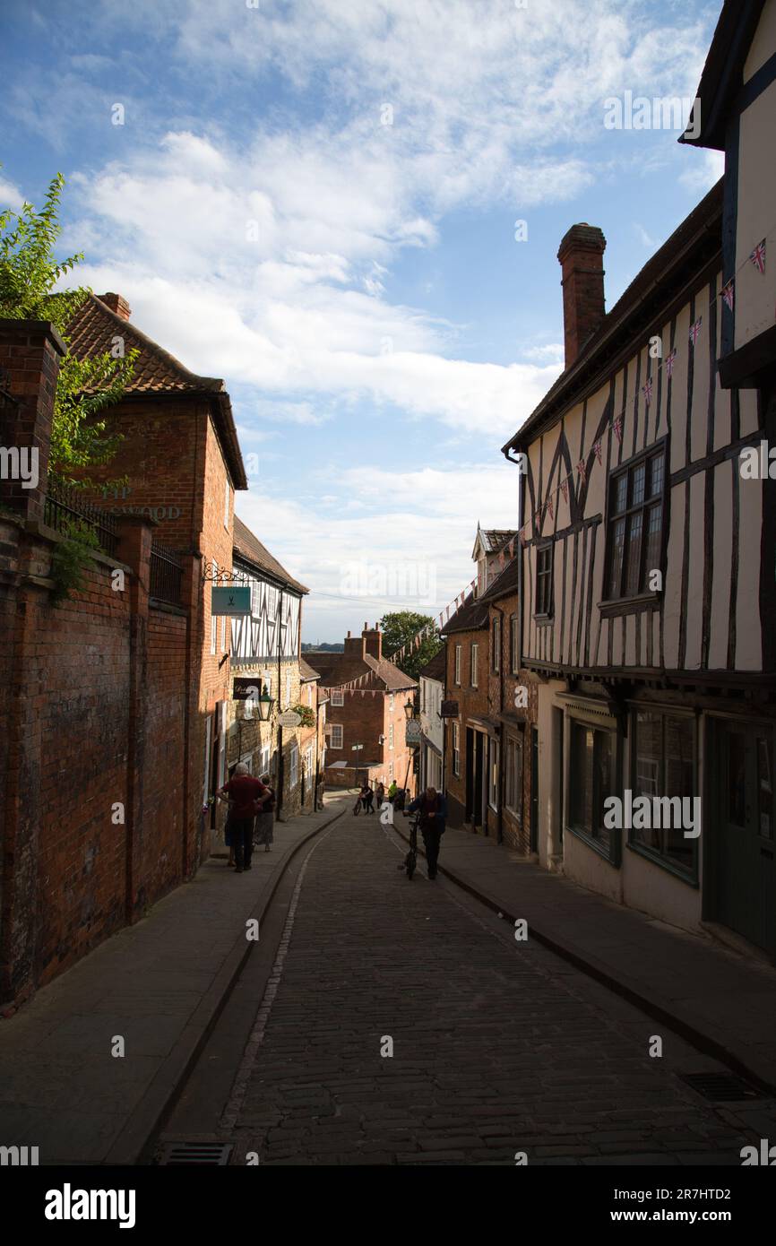 A group of people walking down a quaint cobblestone street in a ...