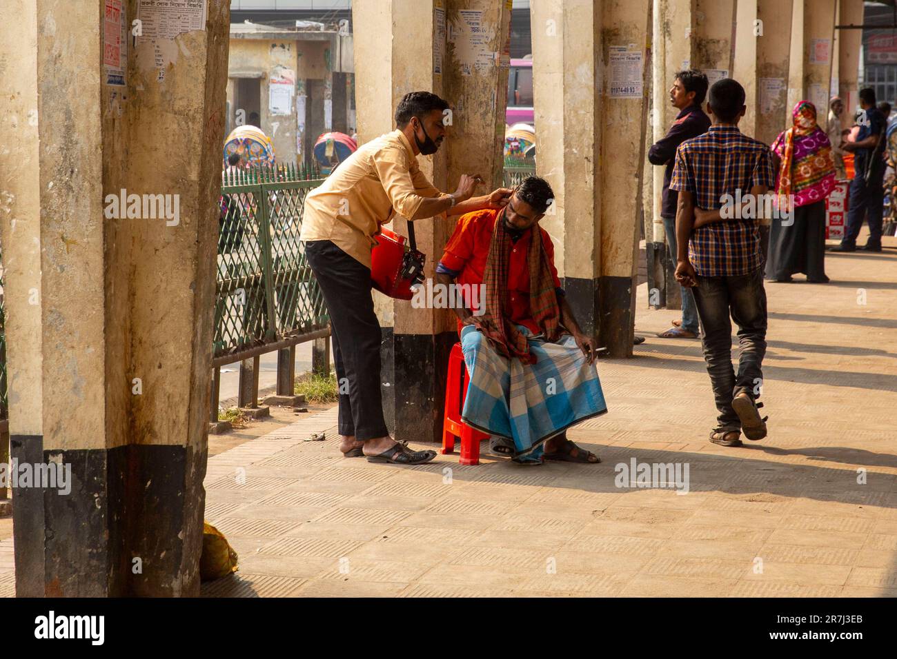 A man gets clean his ears from a street ear-cleaner at Kamlapur Railway Station in Dhaka ...