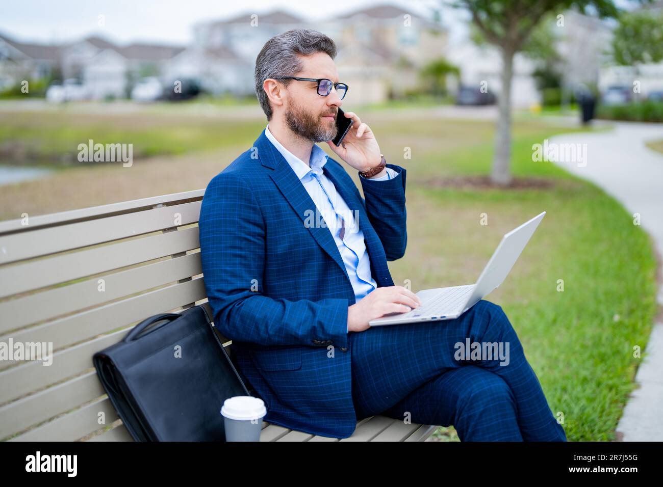 Business talk. Business man talk on phone sitting on a bench in park ...