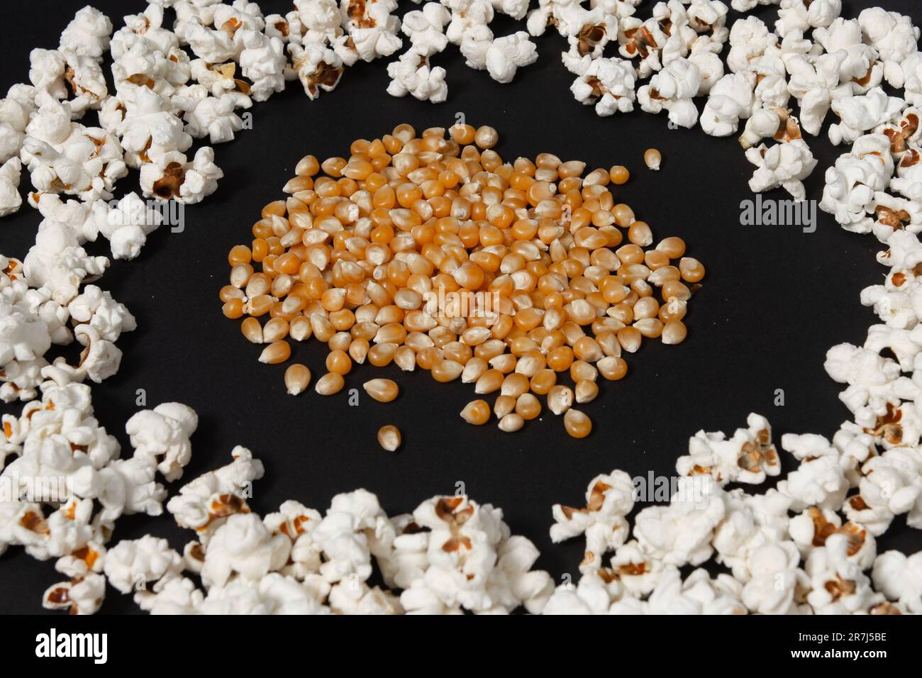 A pile of corn kernels in the middle of a ready-made circle of popcorn ...