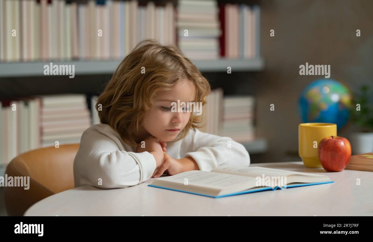 Schoolboy reading book in library. Kids learn to read. Pupil reading ...