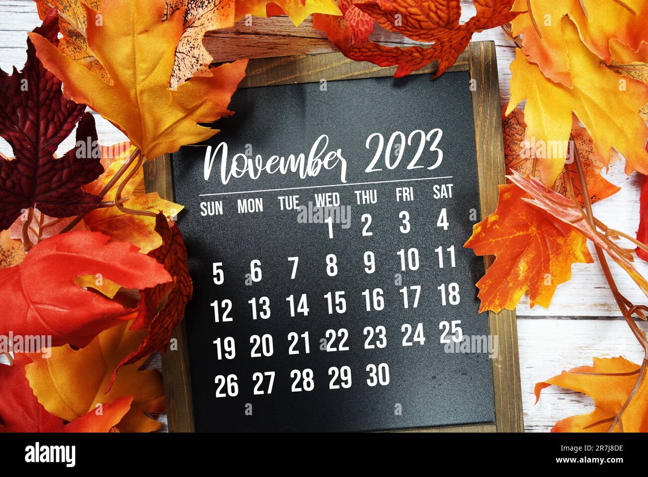 November 2023 monthly calendar with maple leaf on wooden background ...