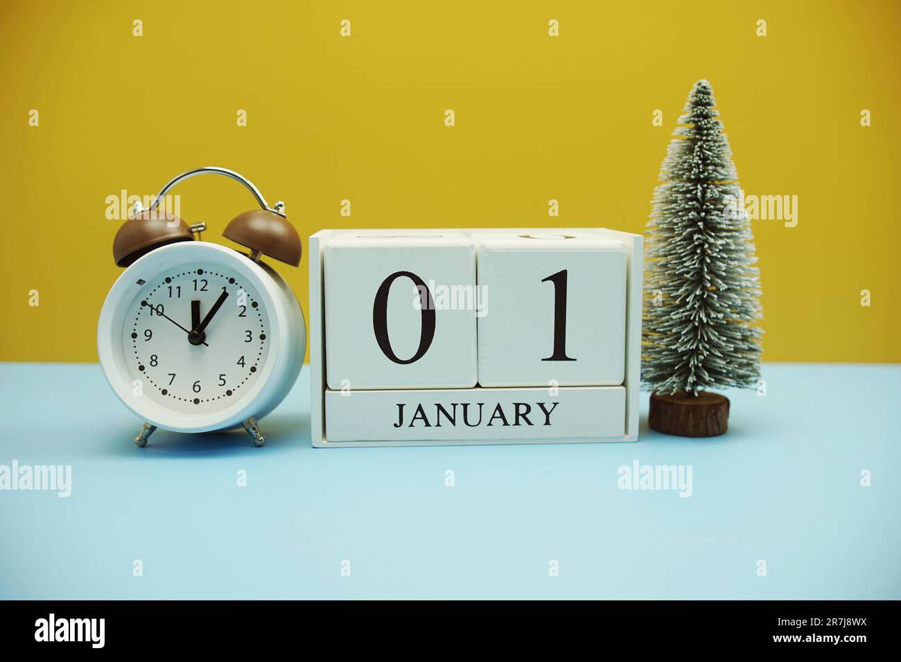 Wooden calendar 1st January with alarm clock and chirtsmas tree on ...