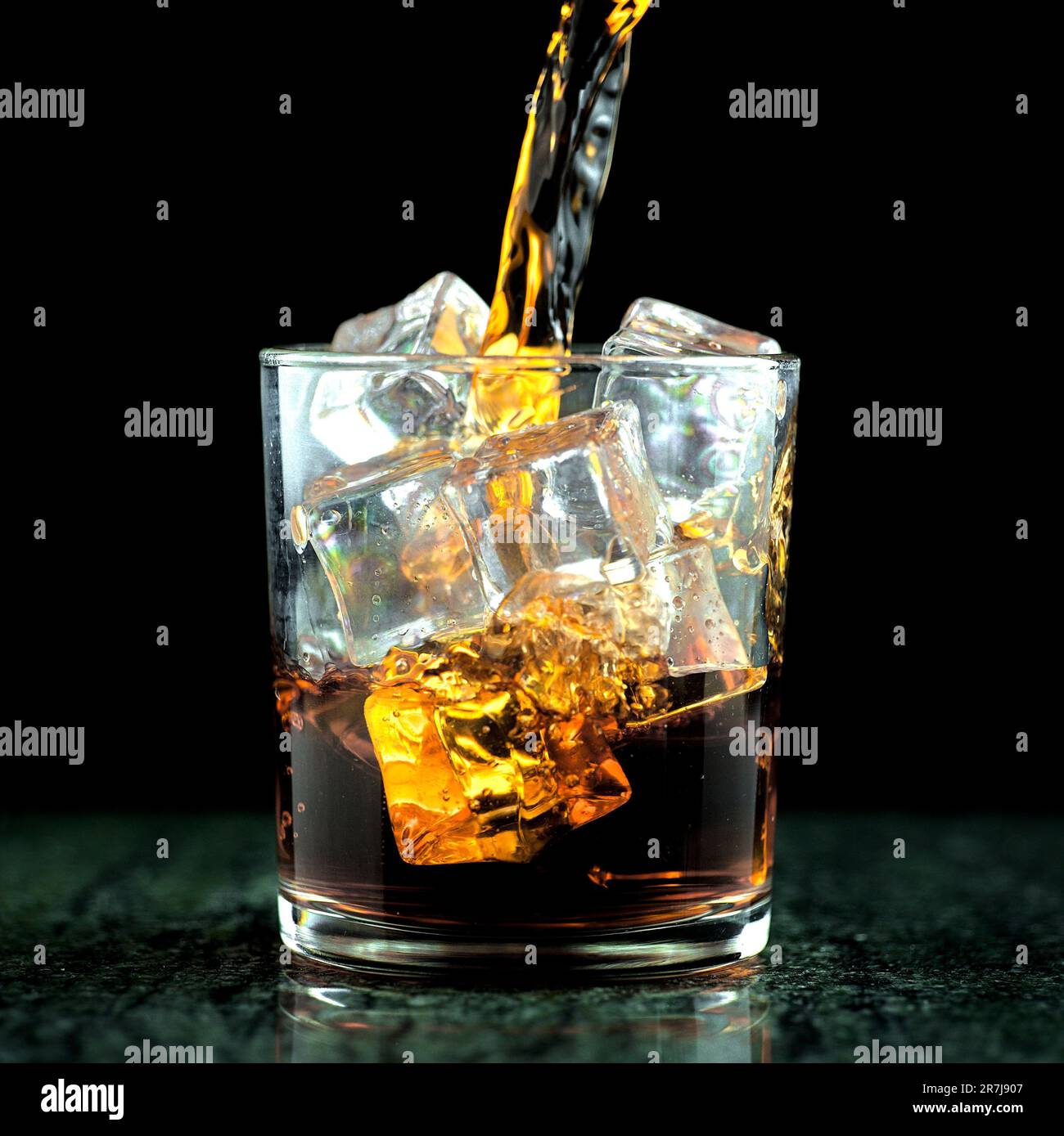 A crystal clear glass of refreshing beverage with cubes of ice ...