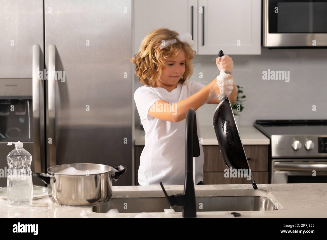 Funny twin boys helping in kitchen with washing dishes. Children having ...