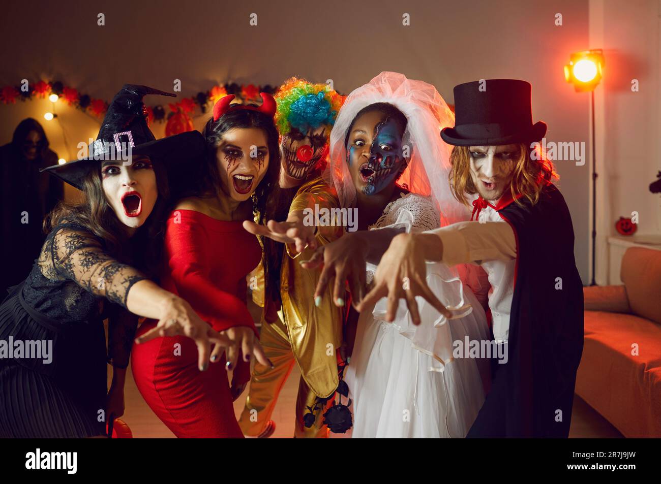 Group portrait of young friends in spooky Halloween costumes saying BOO ...