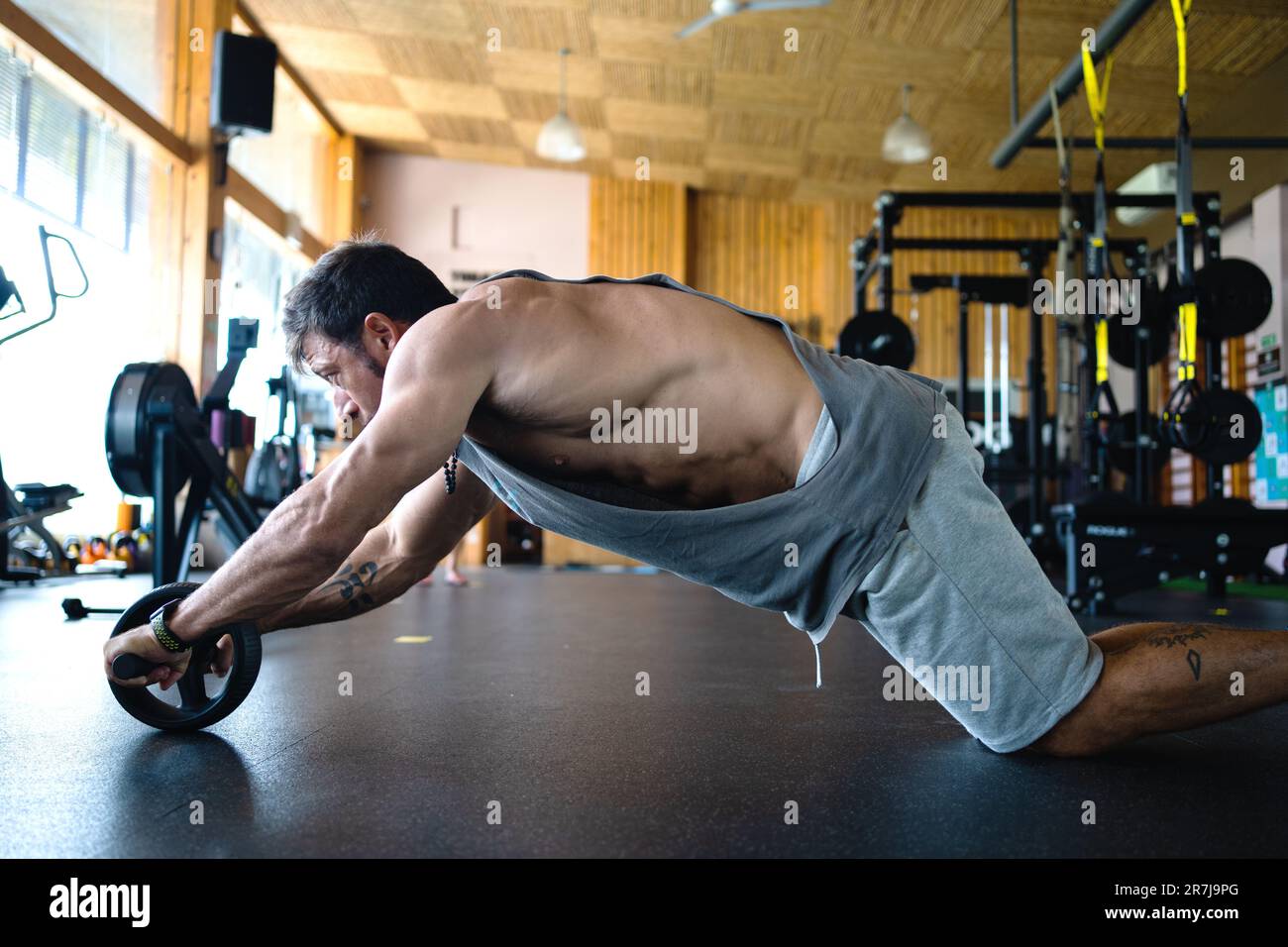 Profile of a strong Man using a abs roller to do exercise on a gym ...