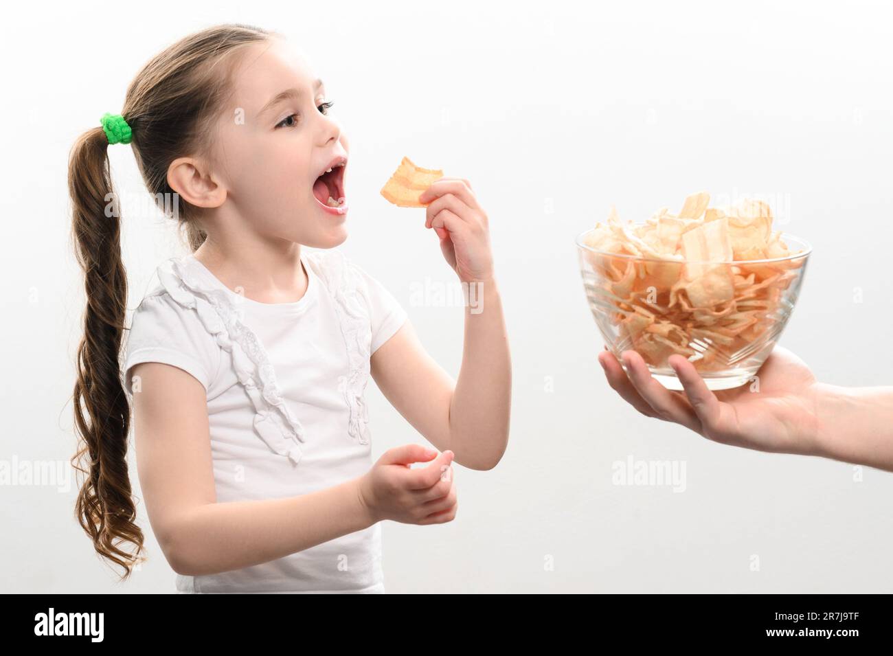 Little girl is given a big bowl of chips snacks with lard, white ...