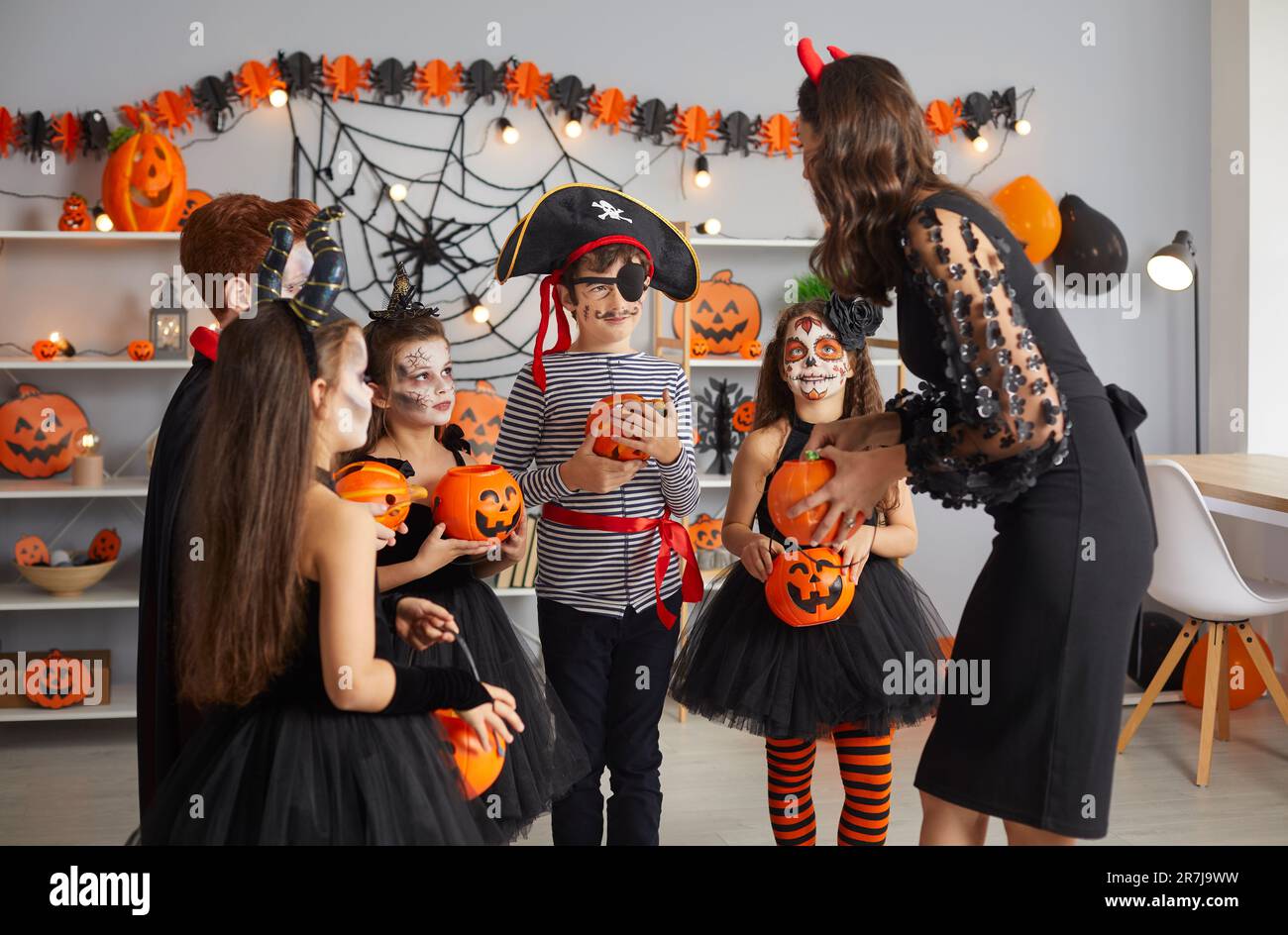 Happy children dressed up in spooky costumes trick or treating at ...