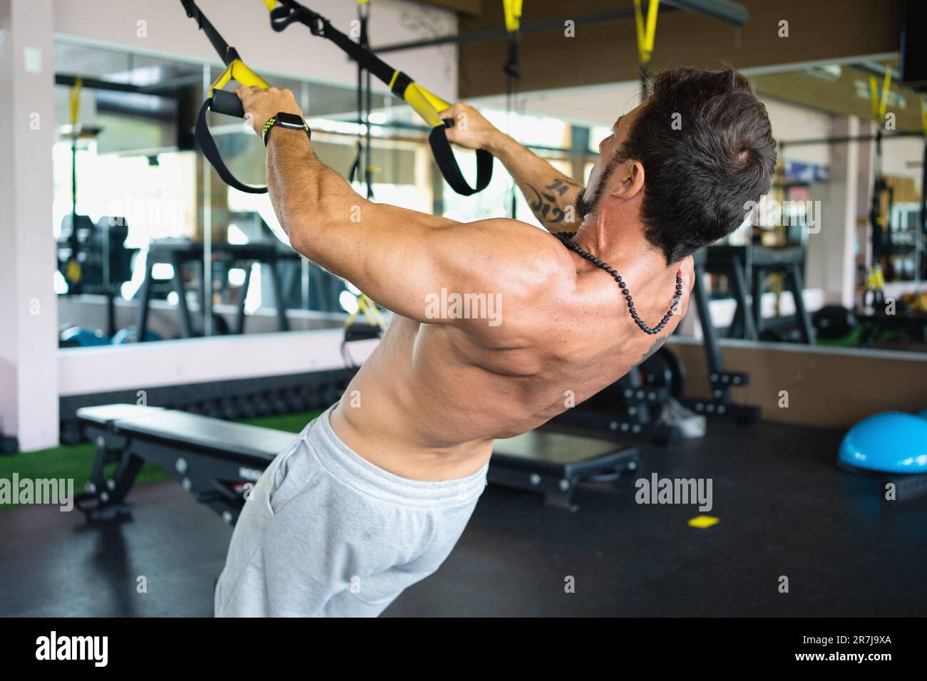 Rear view of a Strong and fit man using trx in gym Stock Photo - Alamy