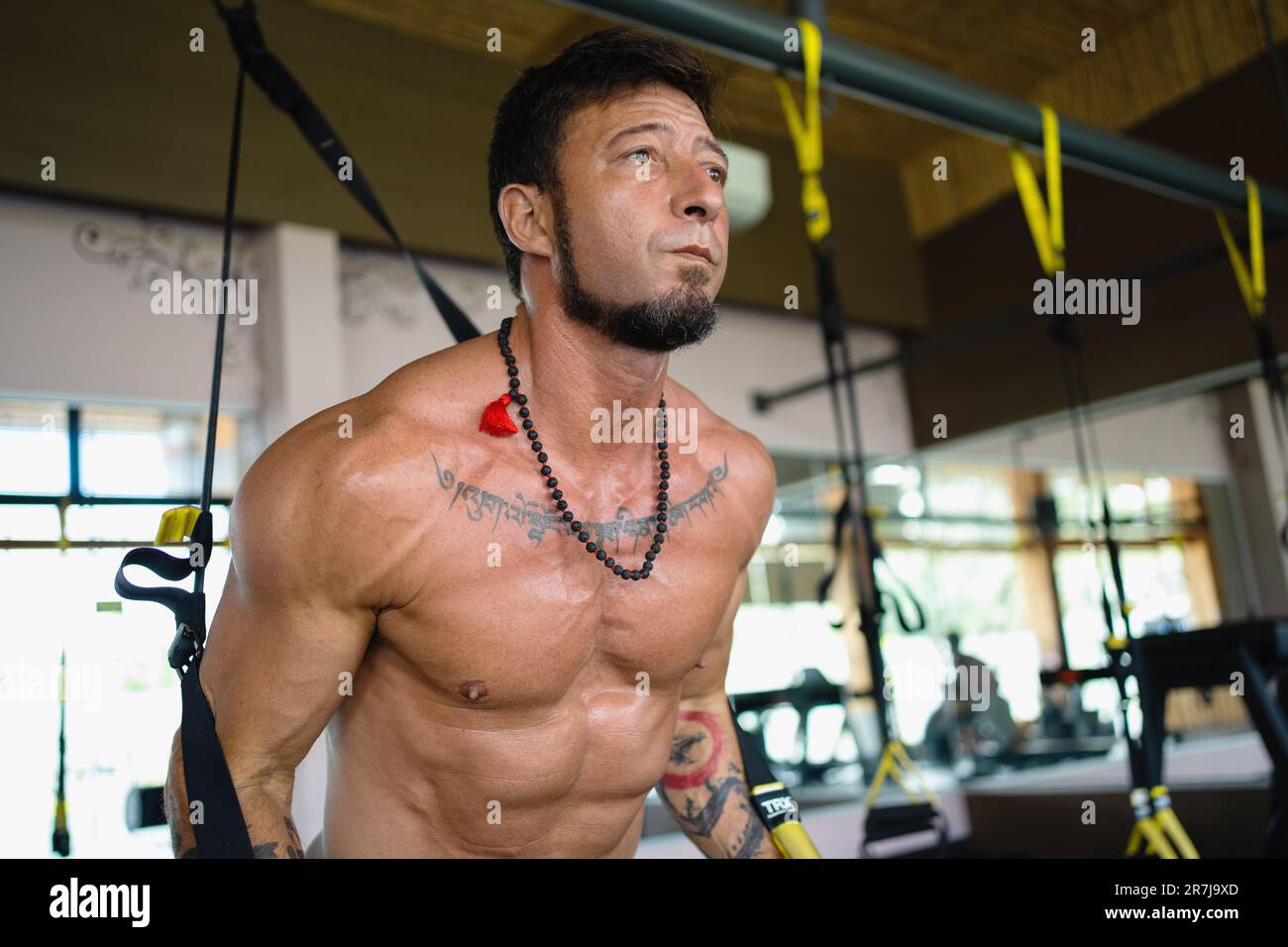 Frontal view of a Strong and fit man using trx in gym Stock Photo - Alamy