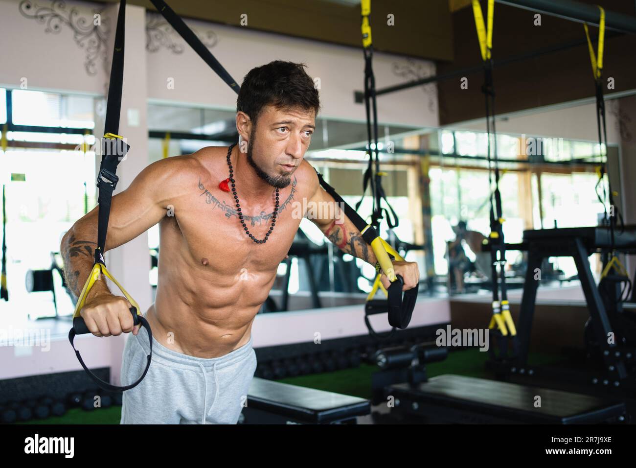 Frontal view of a Strong and fit man using trx in gym Stock Photo - Alamy