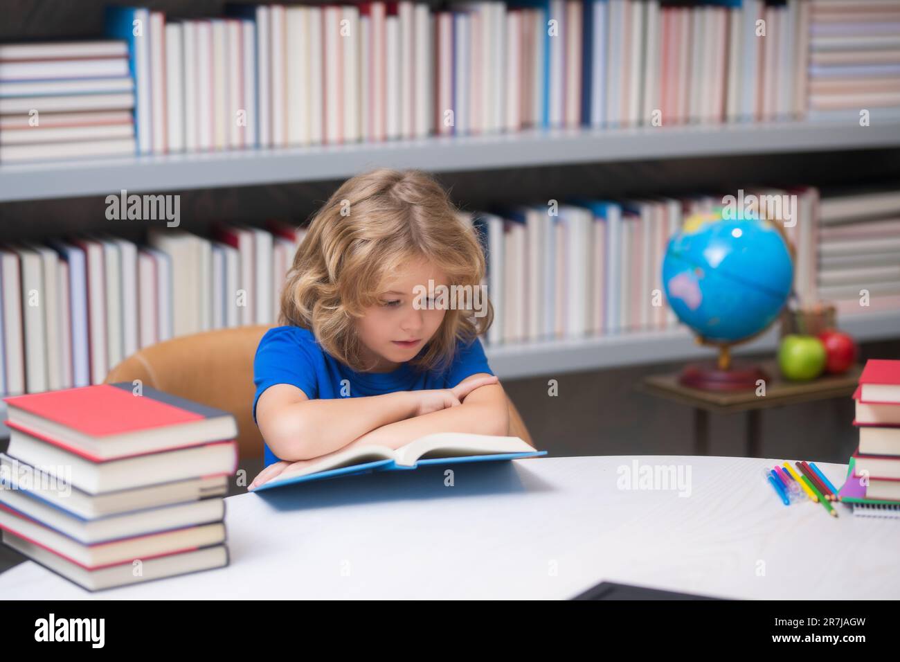 Intellectual child, clever pupil. School boy reading book in library ...