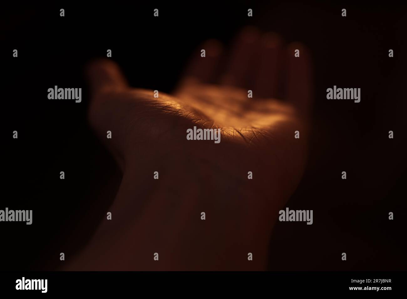 Super closeup of young adult man hand in dark moody lighting. Shallow ...