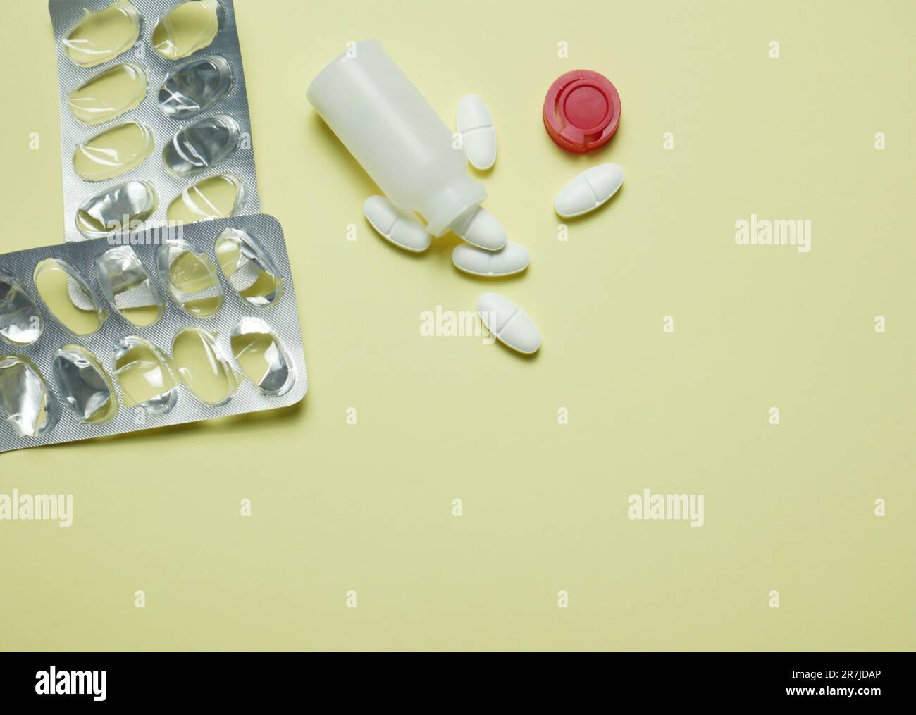 A top view of pharmaceutical medications spilled onto a light yellow ...