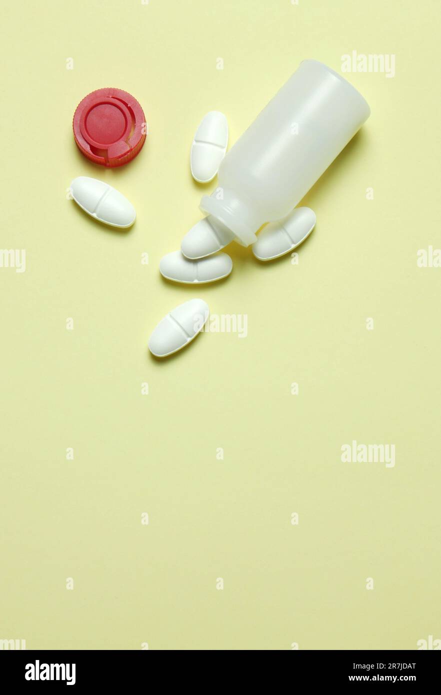 A top view of pharmaceutical medications spilled onto a light yellow ...